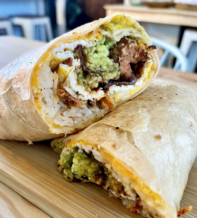 Behold the breakfast burrito in its natural habitat—a perfect cylinder of morning joy where eggs, cheese, and avocado live in harmonious coexistence.