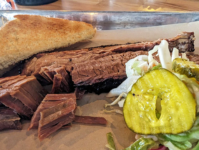Brisket sliced so perfectly you can count the smoke rings, served with pickles that provide that essential acidic counterpoint.