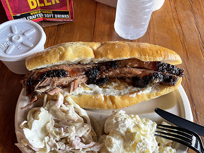 Behold the sandwich of your dreams—bark-crusted brisket nestled in a soft roll, flanked by creamy sides that know their supporting role perfectly.