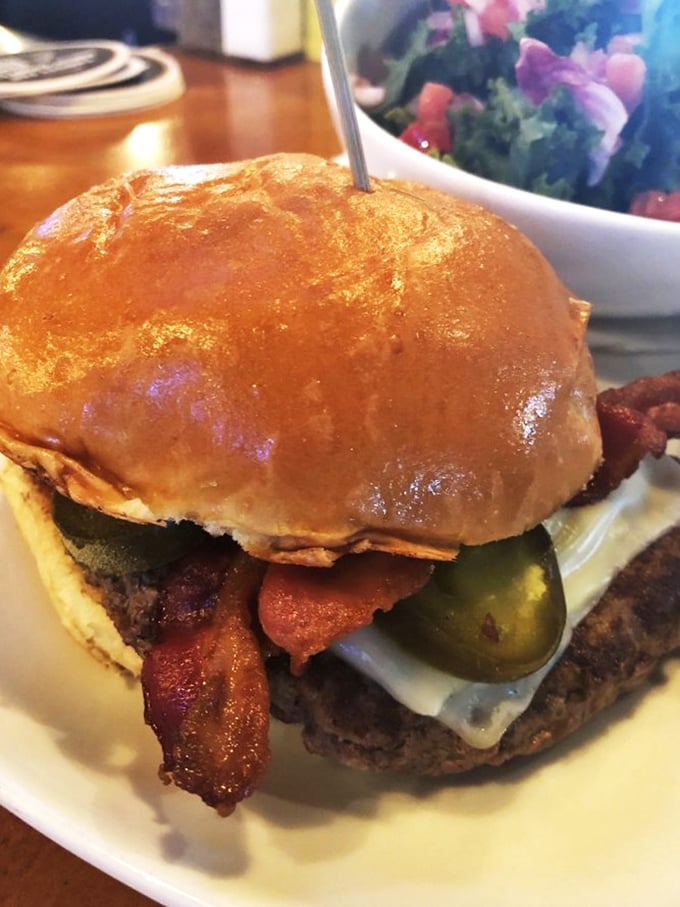This isn't just a burger – it's an architectural marvel of beef, bacon, and pickle that requires both hands, several napkins, and absolutely zero regrets.