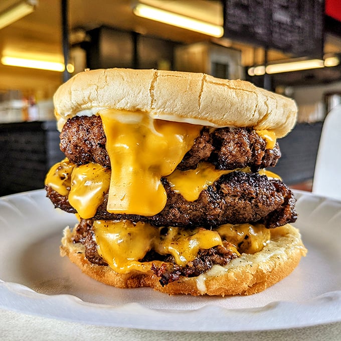 Behold the tower of power! This multi-patty masterpiece with cascading cheese requires both hands, several napkins, and zero regrets.