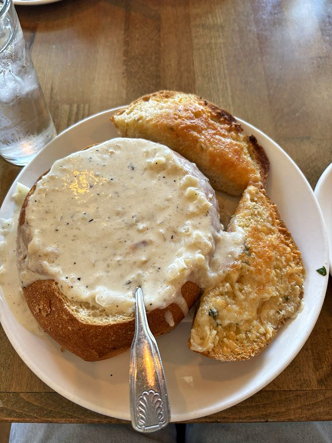 Creamy chowder cascades over a sourdough bread bowl—nature's perfect dishware and the ultimate comfort food marriage.