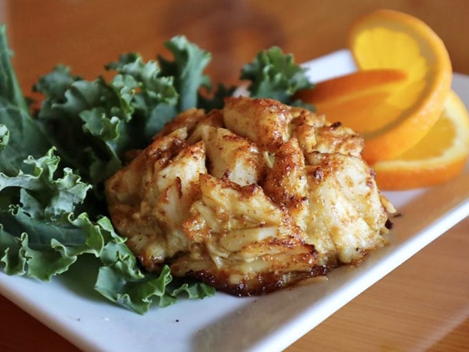Behold the star of the show—a golden-brown crab cake that's more crab than cake, resting on a bed of greens like royalty.