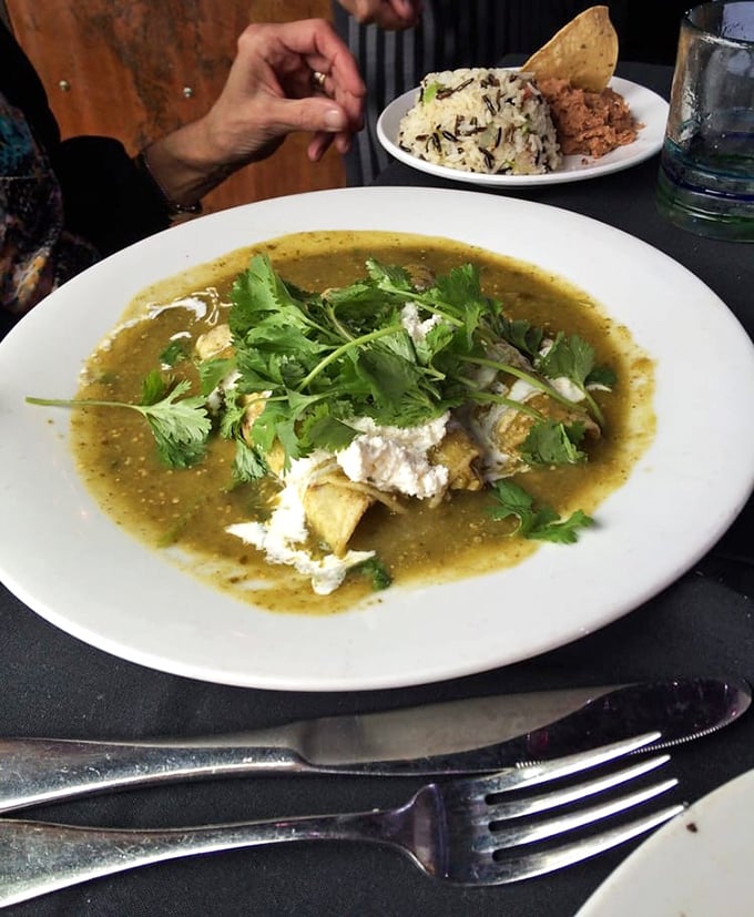 This isn't just an enchilada—it's a flavor revelation swimming in verdant salsa, topped with fresh cilantro and a generous dollop of Mexican cheese.