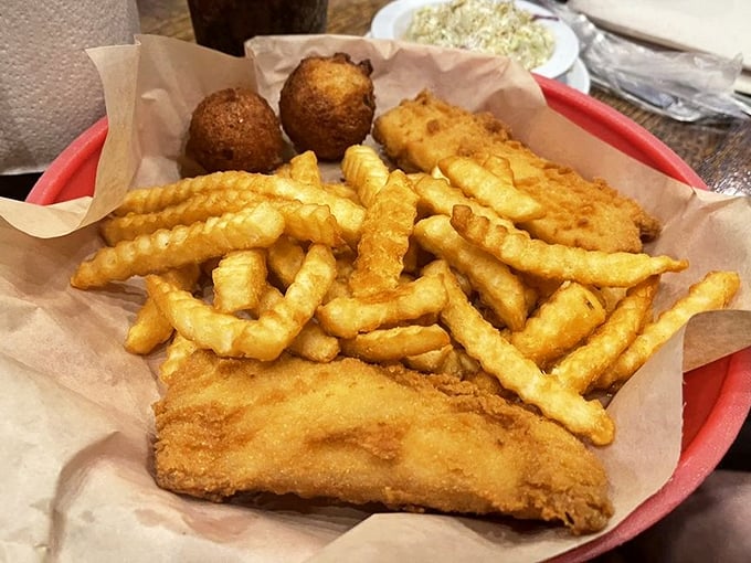 Golden-battered fish resting on a bed of crispy fries with hush puppies standing guard. This isn't just fish and chips—it's edible sunshine.