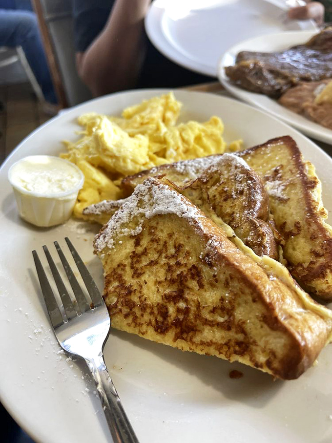 Golden-edged French toast dusted with powdered sugar alongside fluffy scrambled eggs—breakfast perfection that makes you want to high-five the cook.