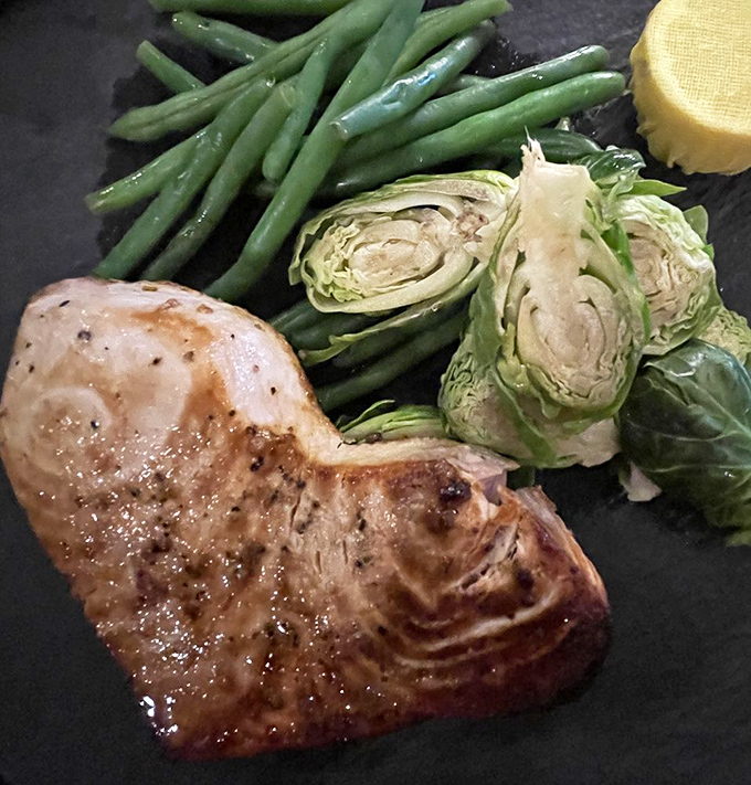 This isn't just grilled fish—it's a masterclass in simplicity. Perfectly seared swordfish with Brussels sprouts and green beans that would make vegetable skeptics reconsider their life choices.