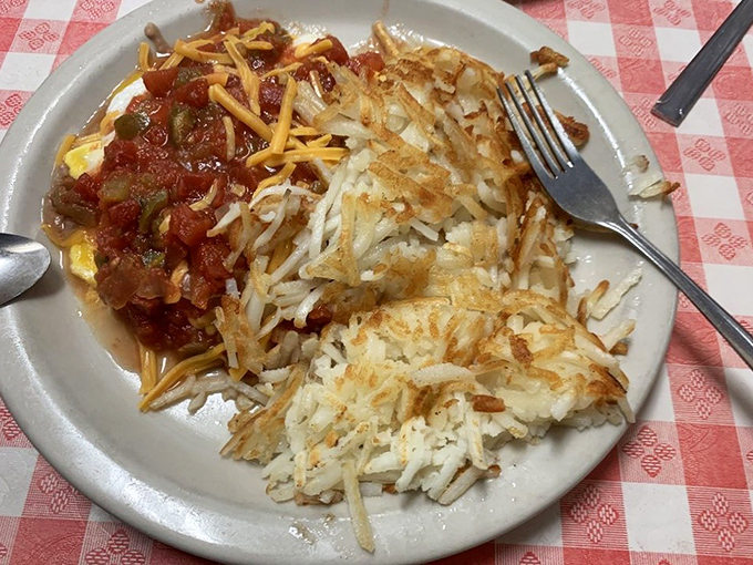 These huevos rancheros don't just arrive on your plate—they make an entrance, with crispy hash browns standing guard beside eggs smothered in homemade salsa and melted cheese.
