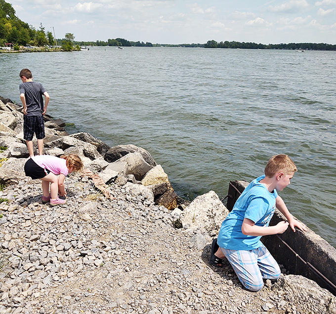Young explorers conducting serious geological research (or just hunting for cool rocks) along Indian Lake's shoreline – childhood curiosity in its natural habitat.