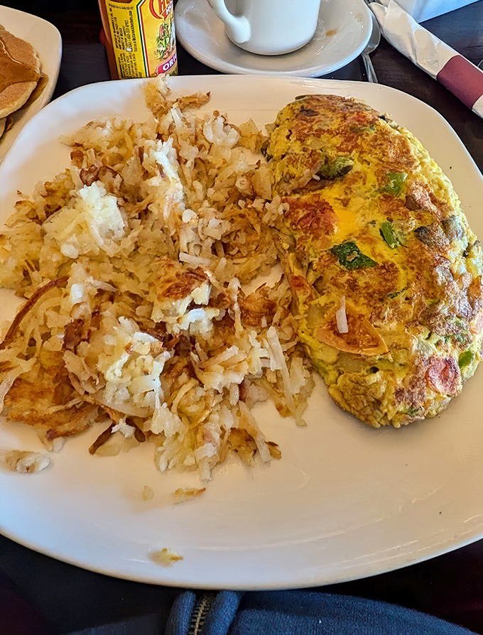 This isn't just an omelet—it's an edible work of art with perfectly crisped hash browns that deserve their own fan club.