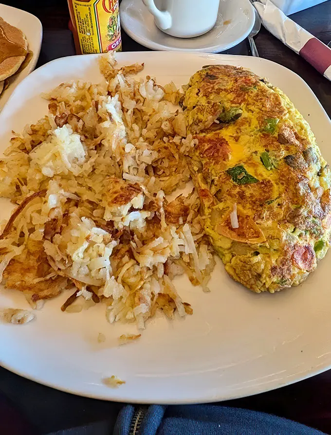 This isn't just an omelet—it's an edible work of art with perfectly crisped hash browns that deserve their own fan club.