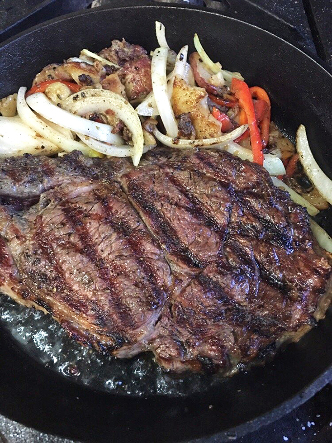 A perfectly seared steak sizzles alongside caramelized onions and peppers—proof that German cuisine isn't just about sausages and sauerkraut.