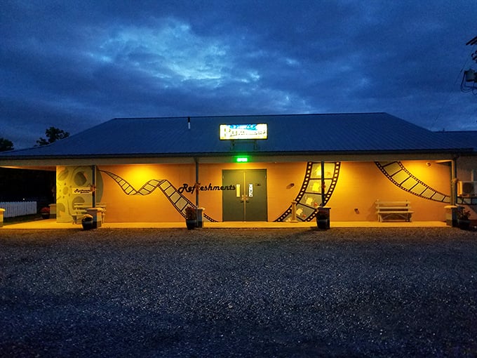The refreshment building glows like a beacon of buttery popcorn hope against the twilight sky. Film strip decorations remind you why you came.