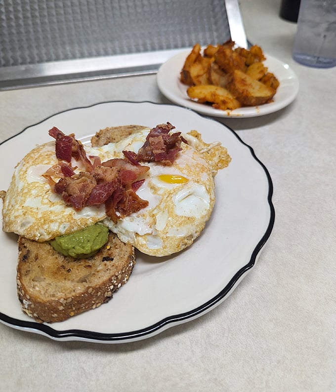 Avocado toast that doesn't require a second mortgage—just perfectly runny eggs, crispy bacon, and creamy avocado on hearty bread that Instagram wishes it could taste.