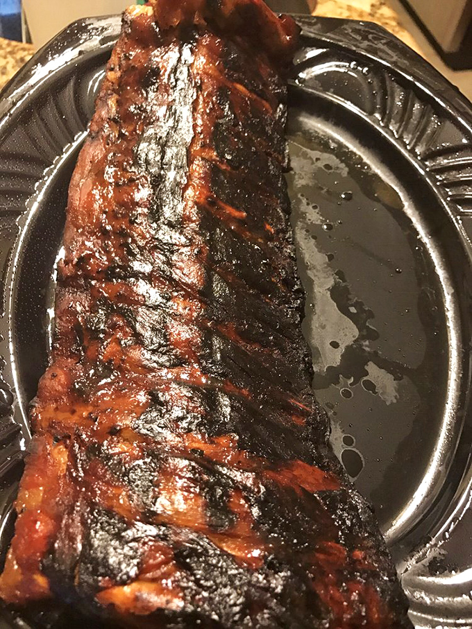 Behold the holy grail of barbecue – ribs with that perfect mahogany bark, glistening with sauce and promising a flavor experience worth every napkin you'll need.