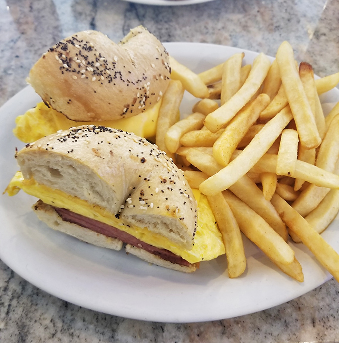 The breakfast sandwich—humanity's greatest invention after coffee. Poppy seed bagel, fluffy eggs, and ham create the holy trinity of morning satisfaction.