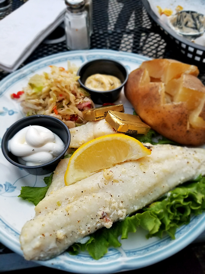 This isn't just fish – it's a pristine fillet of white fish resting on a bed of greens, with butter pats melting like little gold medals.
