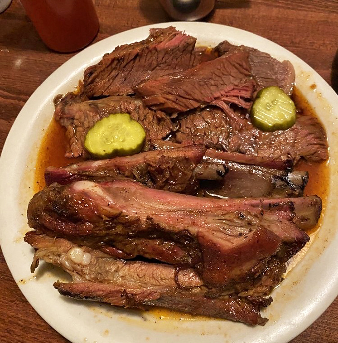 Brisket and ribs sharing a plate like old friends at a reunion. That pickle isn't just garnish – it's the perfect palate refresher.