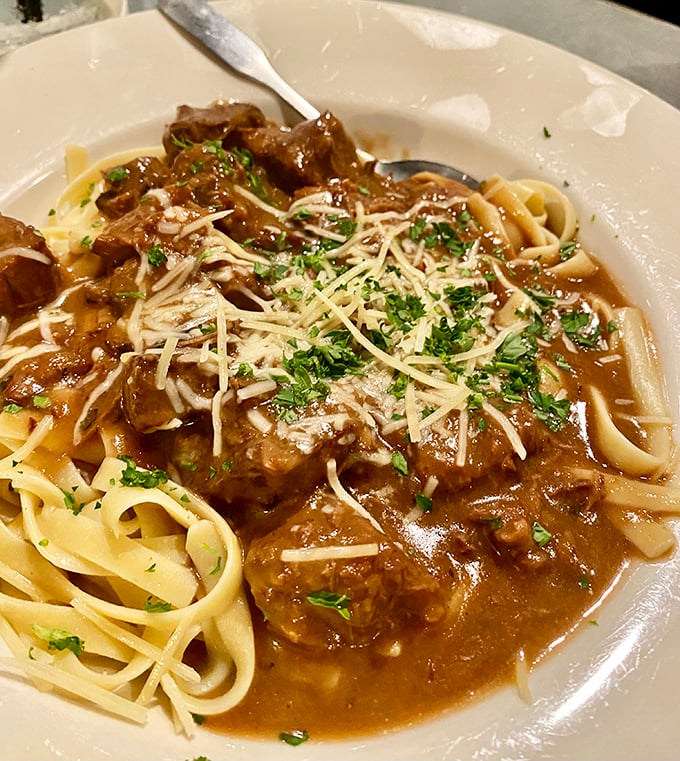 The beef stroganoff arrives like a savory lullaby—tender chunks of beef swimming in rich gravy over pasta, sprinkled with enough parmesan to make an Italian grandmother nod approvingly.