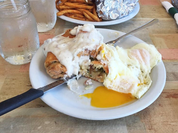 Biscuits and gravy with eggs sunny-side up—comfort food engineering at its finest. That golden yolk is about to create breakfast magic.