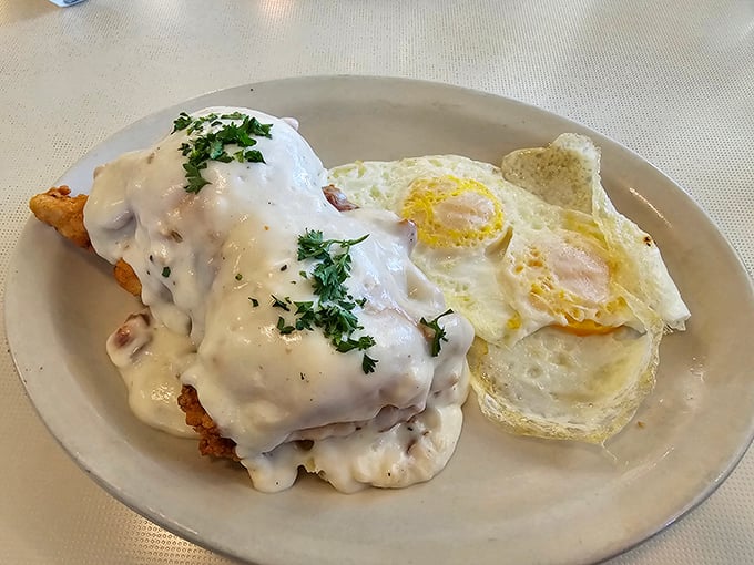 Gravity-defying cream gravy cascades over golden chicken fried steak like a waterfall of comfort. Those sunny-side-up eggs are practically winking at you.