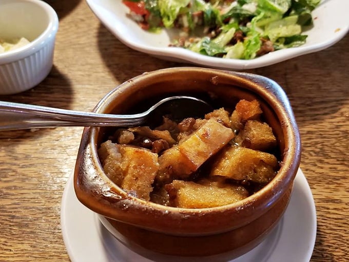 Not your cafeteria bread pudding—this warm, decadent creation swimming in what appears to be a bourbon-laced sauce is the dessert equivalent of a bear hug.