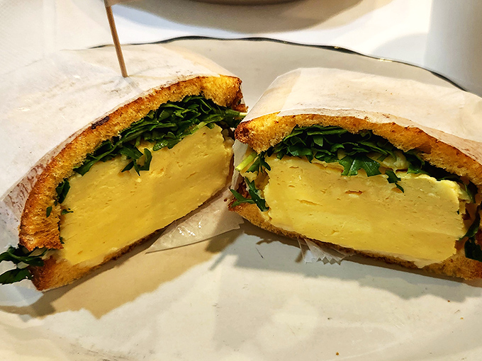 Behold the breakfast sandwich in its natural habitat—a perfect ratio of egg to greens that makes you wonder why all sandwiches can't be this photogenic.