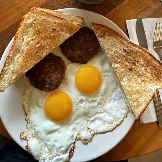 Sunny-side up eggs with perfectly browned sausage patties and toast—a breakfast plate that says "good morning" better than any rooster ever could.