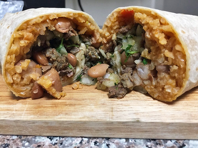Cut into this burrito and witness the perfect cross-section of culinary joy—beans, rice, and perfectly seasoned meat creating a harmony of flavors.