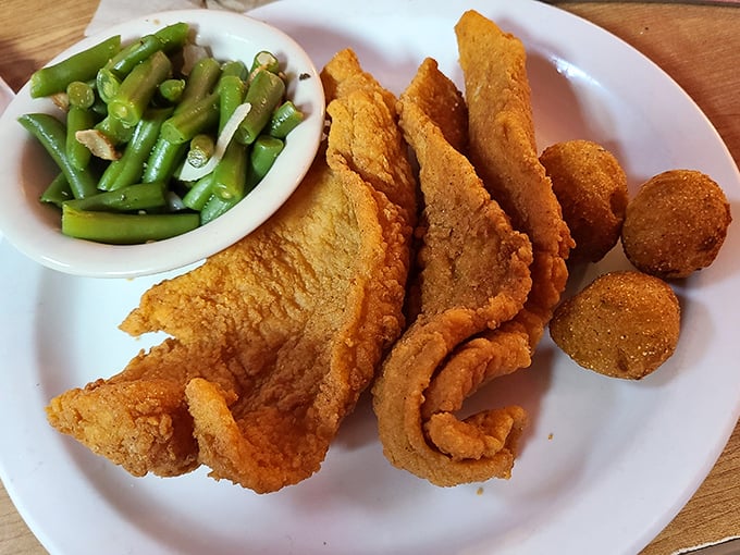 Golden-fried catfish that shatters at first bite, paired with crispy hush puppies and green beans that somehow make you feel virtuous despite the deep-fried festival on your plate.