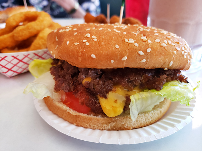 Behold the cheeseburger in its natural habitat—a sesame-speckled bun housing a generous patty where cheese doesn't just melt, it becomes one with the beef.
