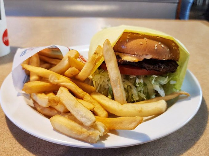 The classic cheeseburger with crispy fries—architectural perfection where each layer knows its role in this timeless American symphony of flavors.