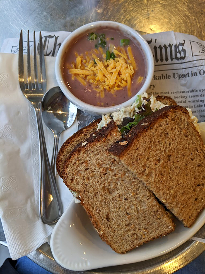 Comfort food perfection: hearty sandwich meets homemade soup, served on newspaper—because good food is always headline-worthy.