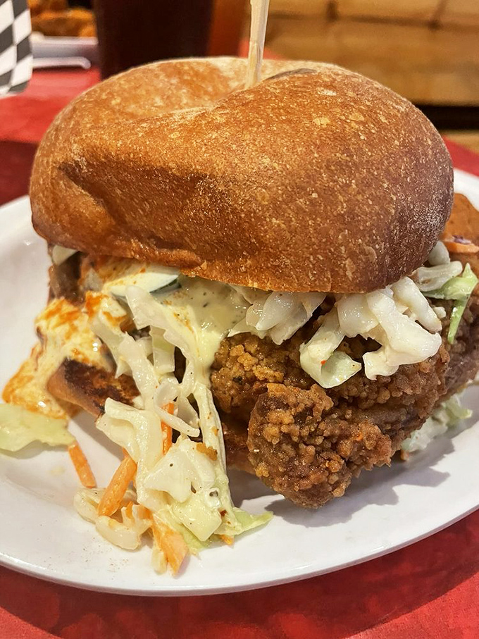 Not your average sandwich! This towering creation features perfectly fried chicken nestled under fresh slaw on a pillowy bun—a handheld masterpiece.