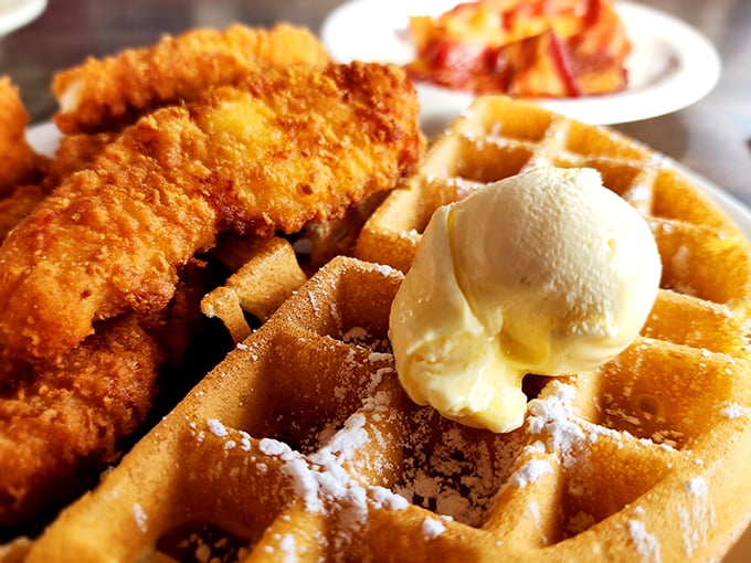 The breakfast equivalent of a standing ovation – crispy fried chicken perched atop a golden waffle with butter melting into every perfect square.