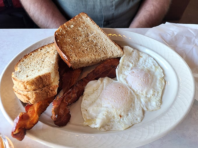 The holy trinity of breakfast perfection: eggs with golden centers, bacon with the ideal crisp-to-chew ratio, and toast that's actually worth eating.