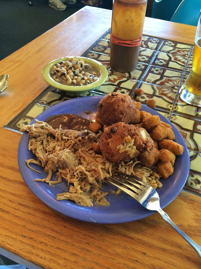 Corn fritters, pulled pork, and fried okra create the holy trinity of Southern comfort on one plate.