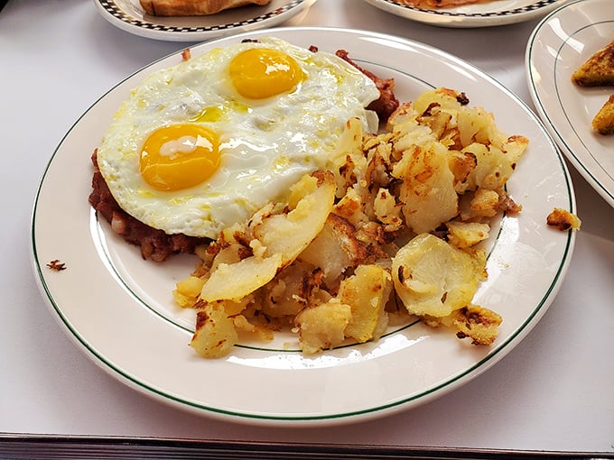 Two sunny-side-up eggs perched atop a mountain of home fries—proof that breakfast is the most important art form of the day.
