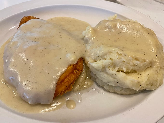 Country fried steak swimming in creamy gravy alongside a perfect biscuit. This plate doesn't just feed your body—it hugs your soul.