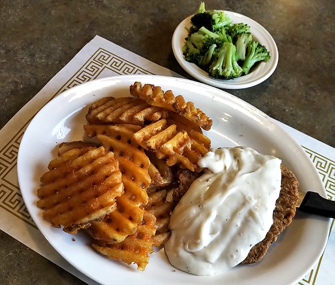 Country fried steak with waffle fries and gravy—the holy trinity of comfort food that makes your cardiologist wince and your soul sing.