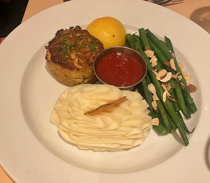 This isn't just any crabcake—it's architectural perfection with golden-brown edges, served with whipped potatoes that could make a cloud jealous.