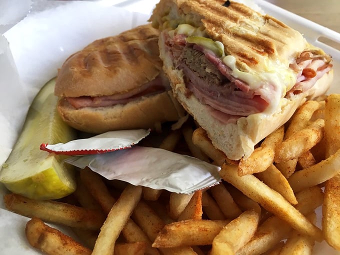 The Cuban sandwich arrives like a pressed postcard from heaven—layers of ham, pork, and cheese creating the kind of harmony that would make the Rat Pack jealous.