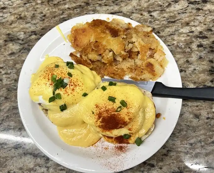 Eggs Benedict with a hollandaise sauce that defies the laws of breakfast physics – somehow both rich and light, dusted with paprika for that extra touch.