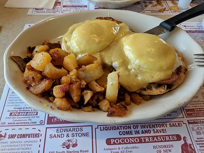 Eggs Benedict done right—hollandaise cascading over Canadian bacon and English muffins. Paired with those seasoned home fries, it's morning nirvana on a plate.
