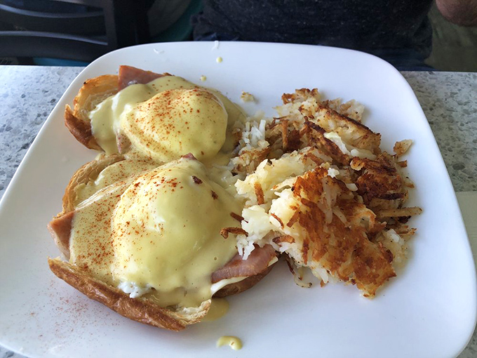 Eggs Benedict done right—poached eggs perched atop Canadian bacon with hollandaise cascading down like a yellow waterfall of happiness.