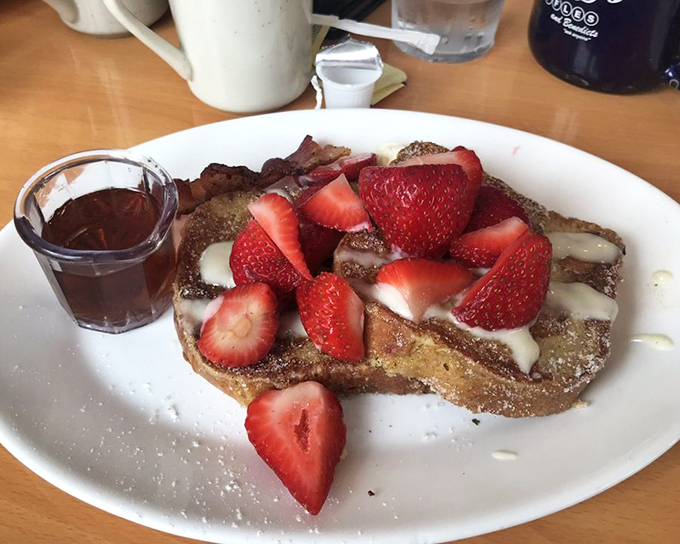 This isn't just French toast—it's a strawberry-studded island of crispy-edged, custardy bread heaven with maple syrup shores.