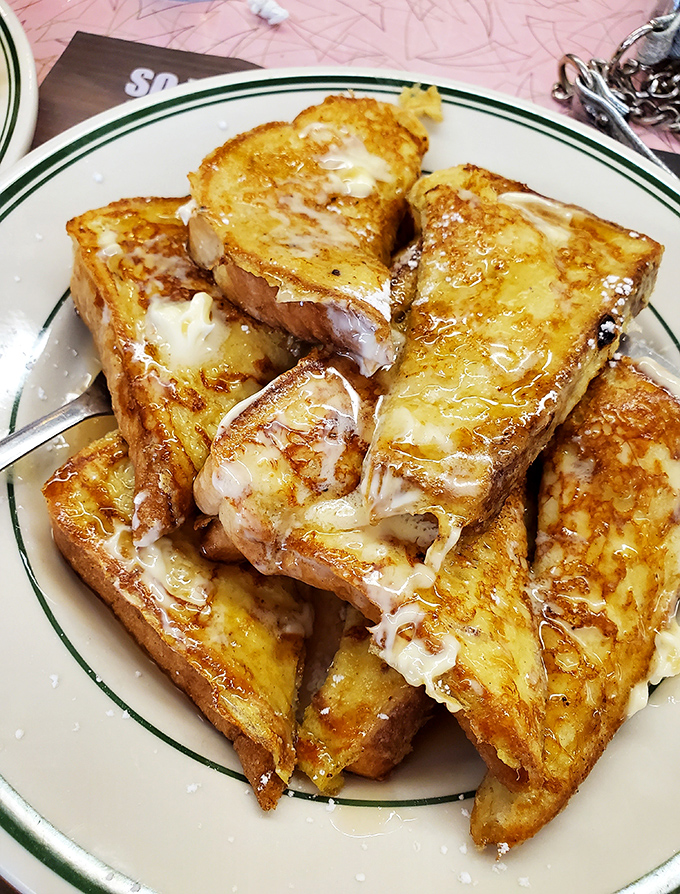 French toast that doesn't need a passport to impress—thick-cut, golden-brown, and dripping with melty goodness that would make your cardiologist wince.