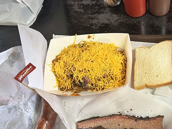 Frito Pie topped with a mountain of cheese—proof that sometimes the best culinary experiences come in humble cardboard boats.
