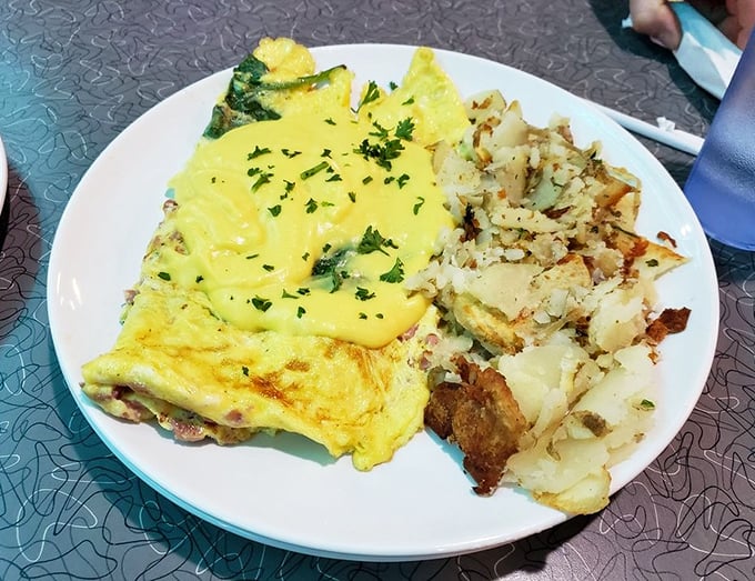 This isn't just an omelet—it's architecture. Layers of ham, cheese, and spinach create the foundation, while hollandaise adds the golden roof.