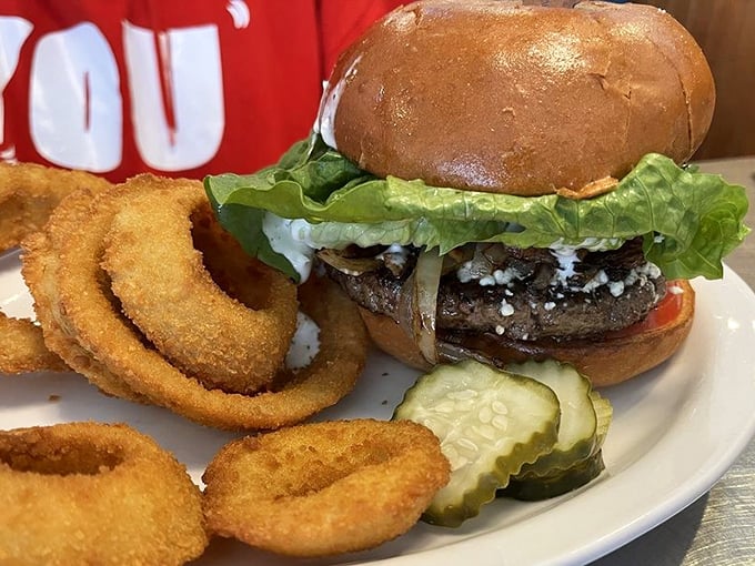 This isn't just a burger—it's architectural perfection. Golden onion rings stand at attention alongside a masterpiece that makes fast food chains weep with inadequacy.